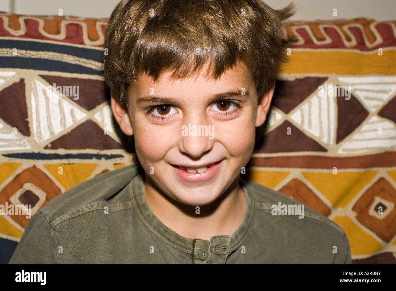 Face of boy Olly aged nine with large brown eyes smiling and looking ...