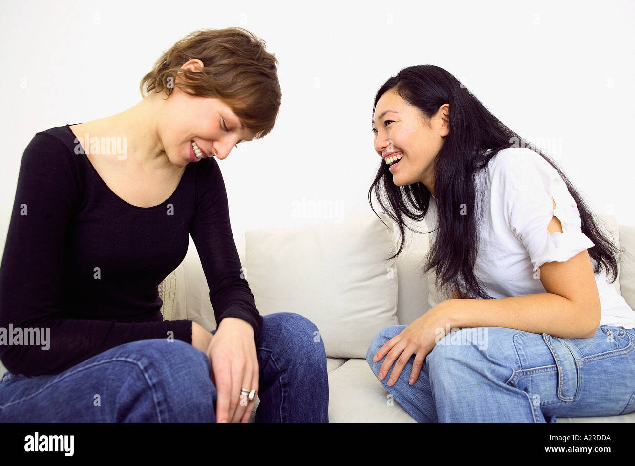 Two women laughing on sofa Stock Photo - Alamy