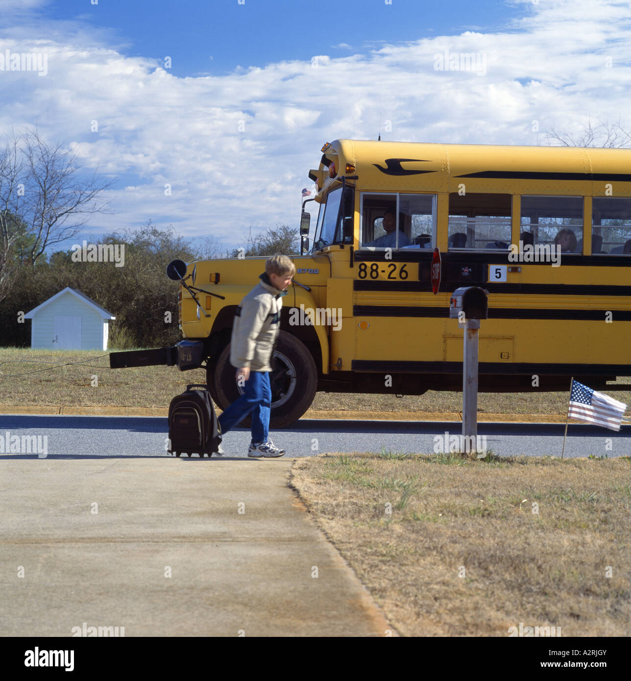 BOY WALKING BY SCHOOL BUS Stock Photo - Alamy