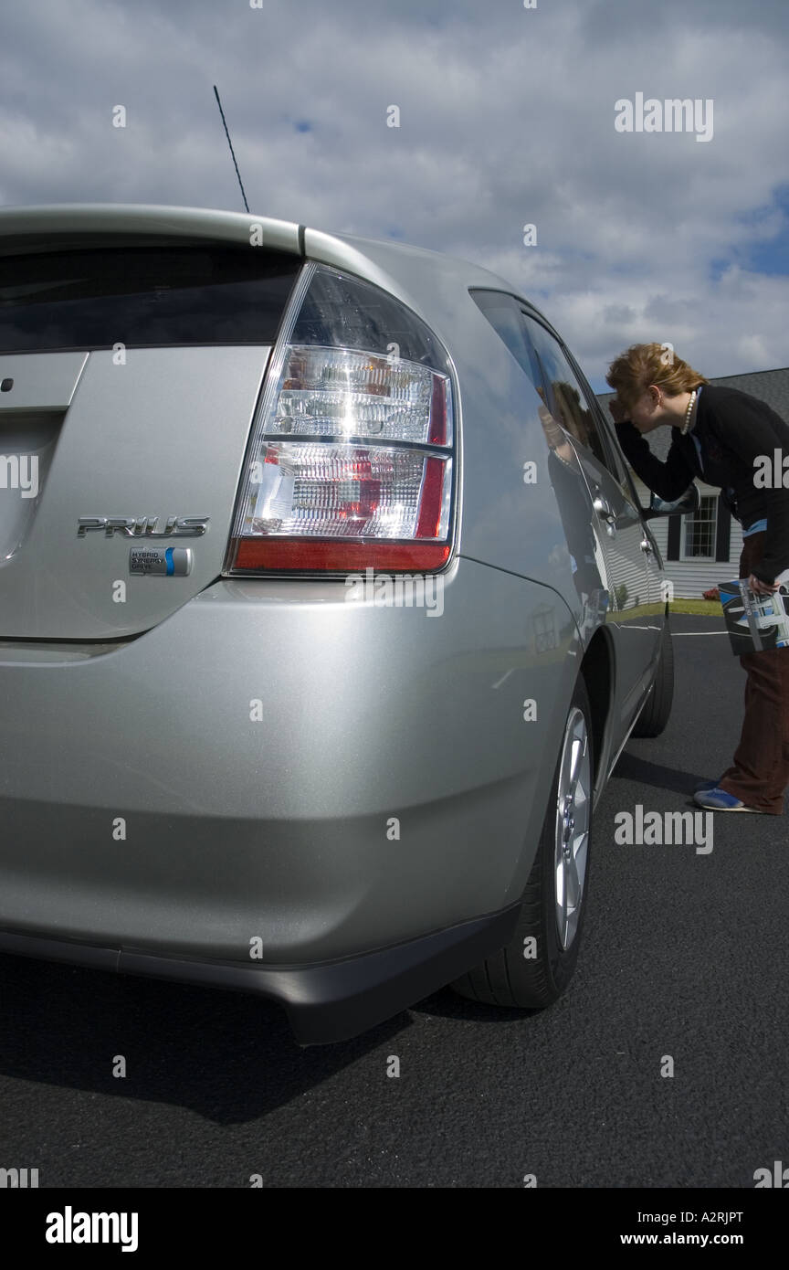 YOUNG WOMAN LOOKING AT 2004 TOYOTA PRIUS GASOLINE-ELECTRIC HYBRID CAR ...