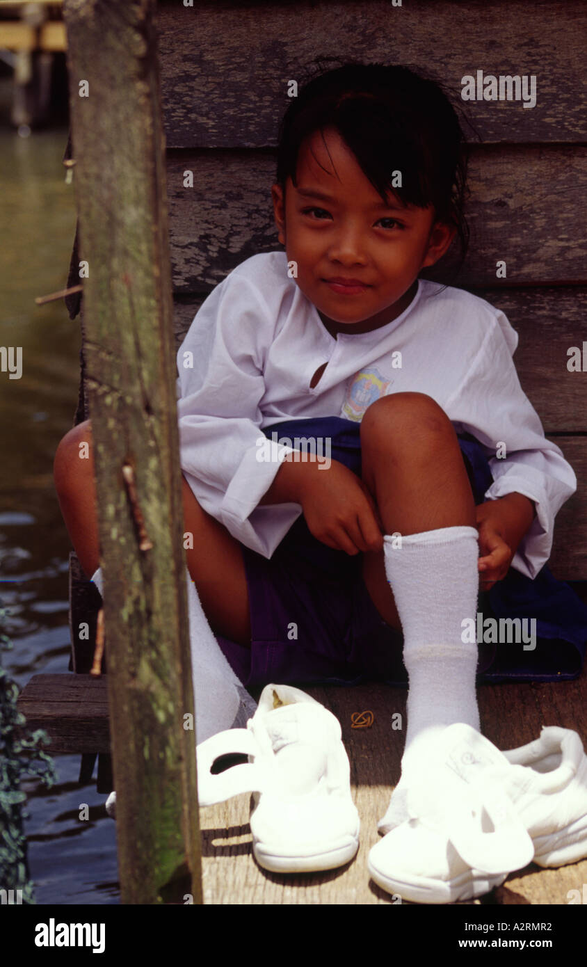 Vertical portrait of Borneo school girl putting on her uniform ...