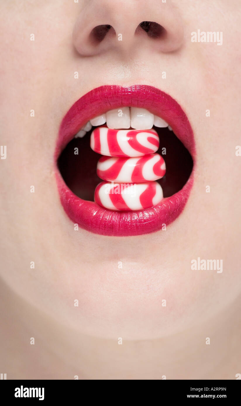 Young woman holding sweets between teeth close up Stock Photo - Alamy