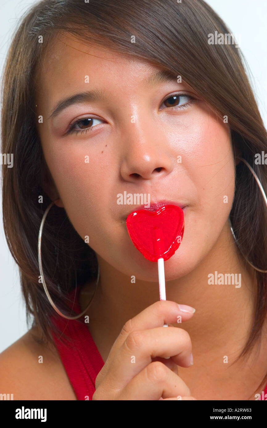 Youg asian woman eating a heart-shaped lollipop Stock Photo - Alamy