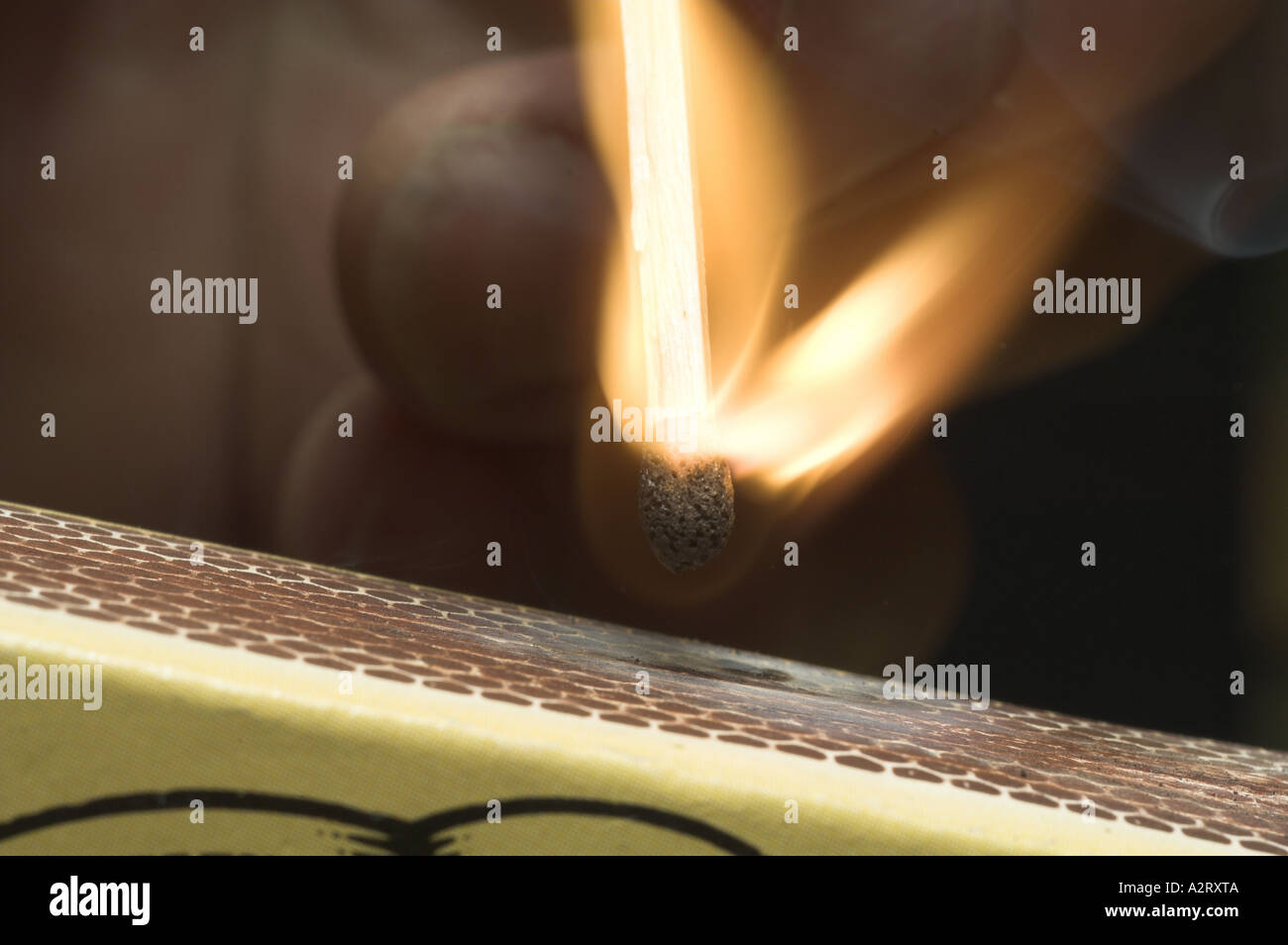 Safety match being struck on side of large matchbox showing match head ...