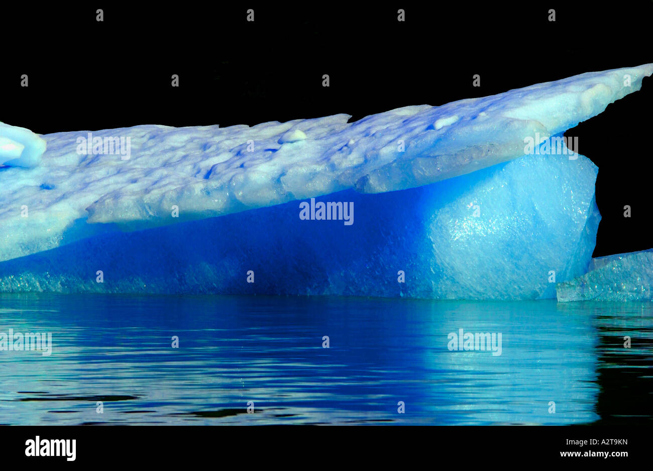 A single iceberg floating in Conte Bay Alaska isolated against a dark ...