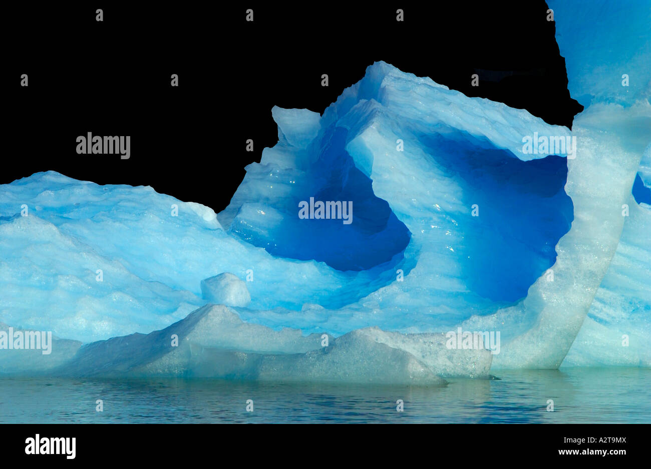 a single iceberg floating in Conte Bay Alaska isolated against a dark ...
