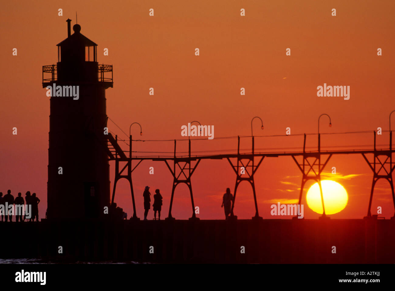 Viewers on pier watching the sun set into lake michigan hi-res stock ...