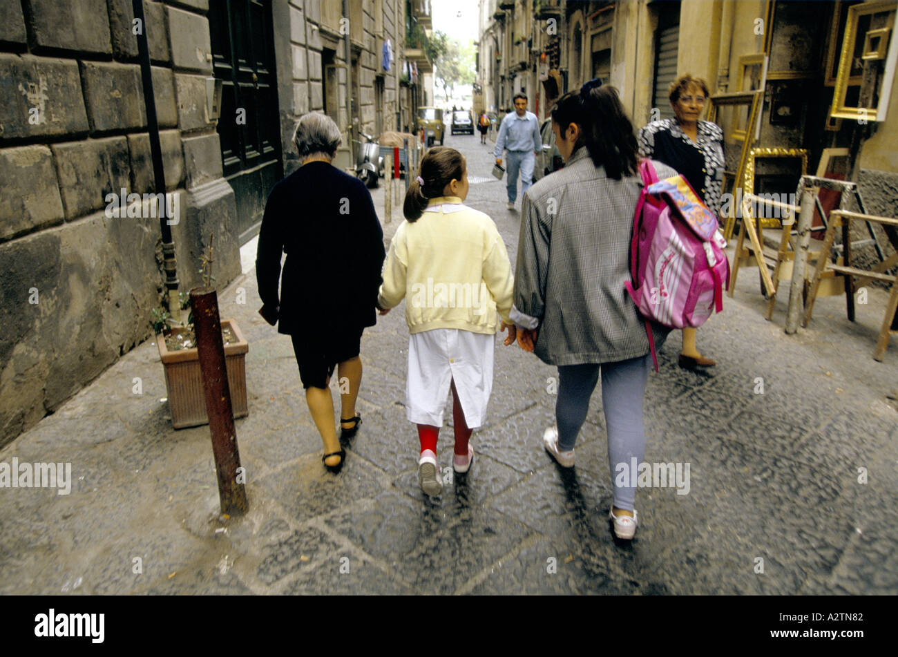 three generations of women walking along narrow street in naples italy ...