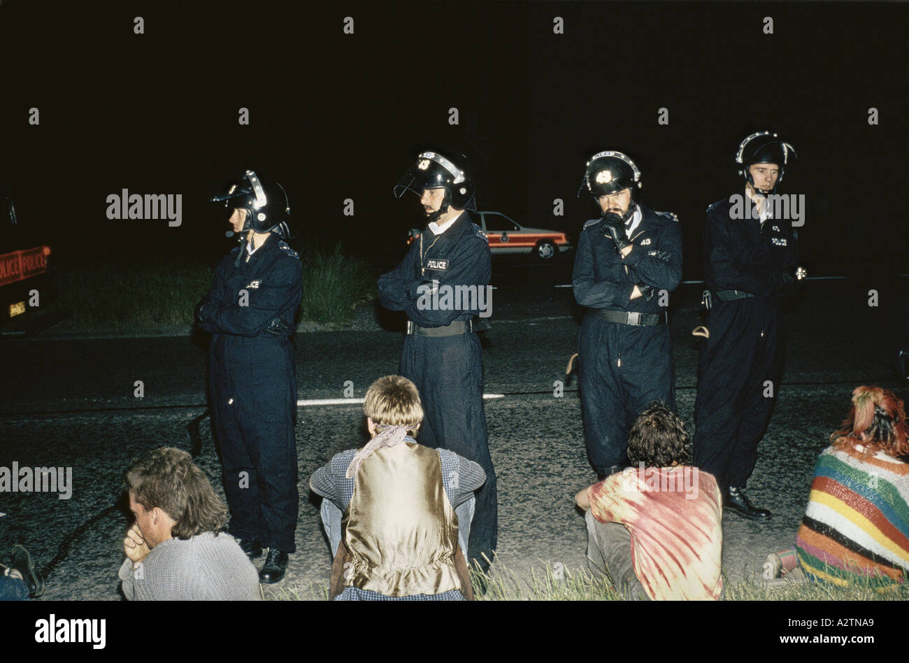 hippies sitting on ground confronting police with helmets standing ...