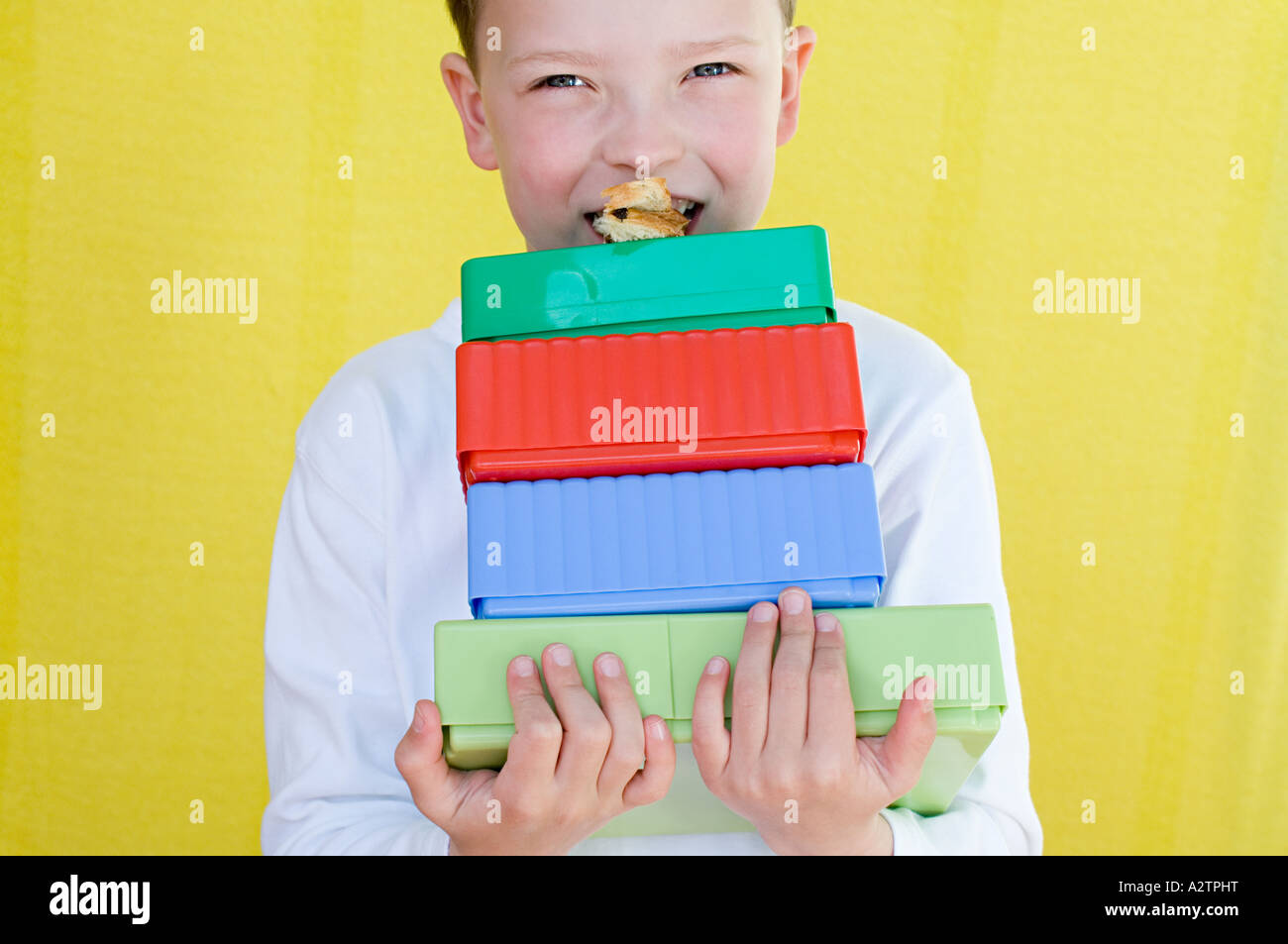 Boy eating snack on top of lunch boxes Stock Photo - Alamy