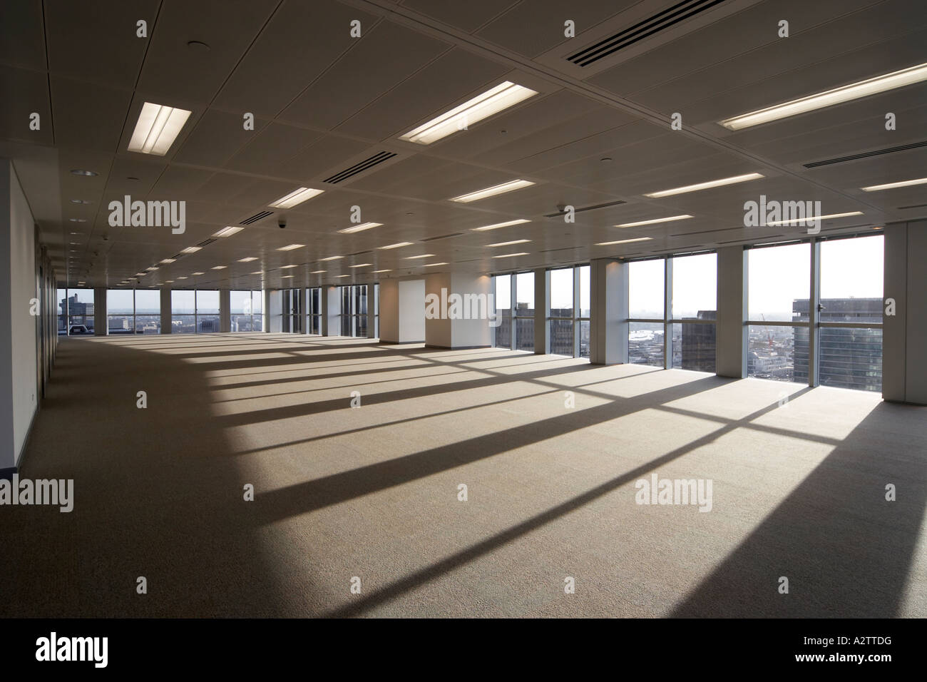 Empty floor with evening sunlight coming through large windows of tall ...