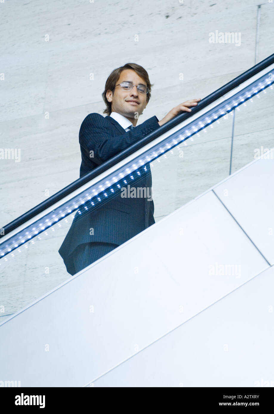 Businessman going up on escalator, portrait Stock Photo - Alamy