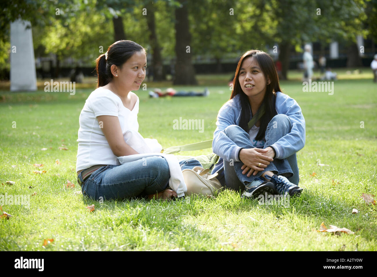 Two asian girls chatting in evening sunlight in Grosvenor Square in ...