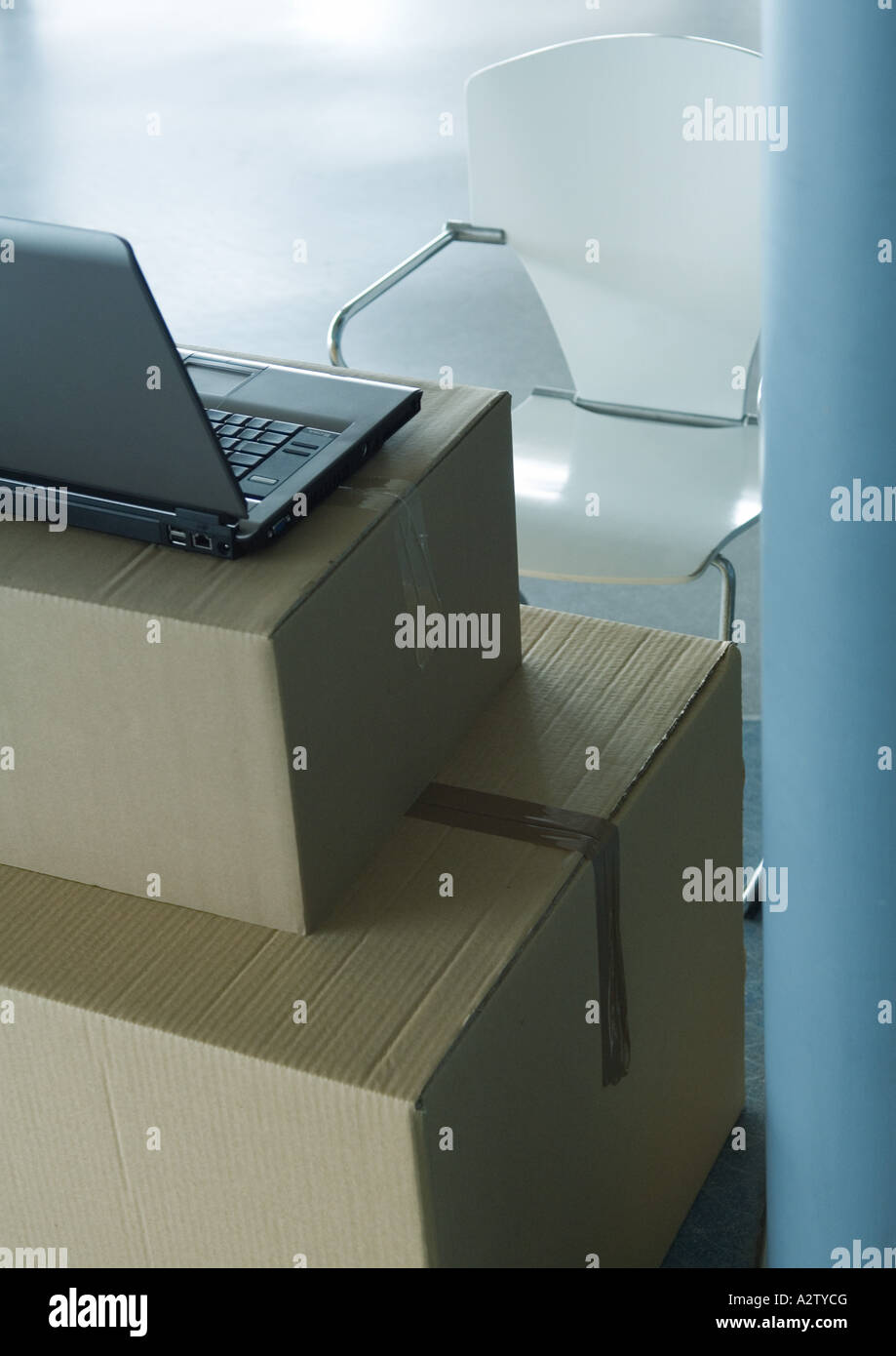 Open laptop on stack of cardboard boxes, and empty chair Stock Photo ...