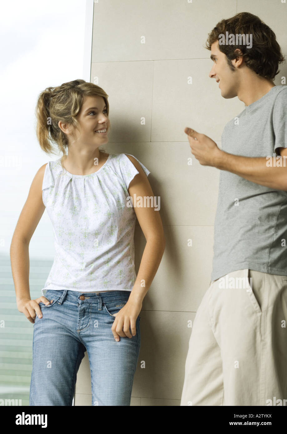 Young man and woman leaning against wall, talking and smiling Stock ...