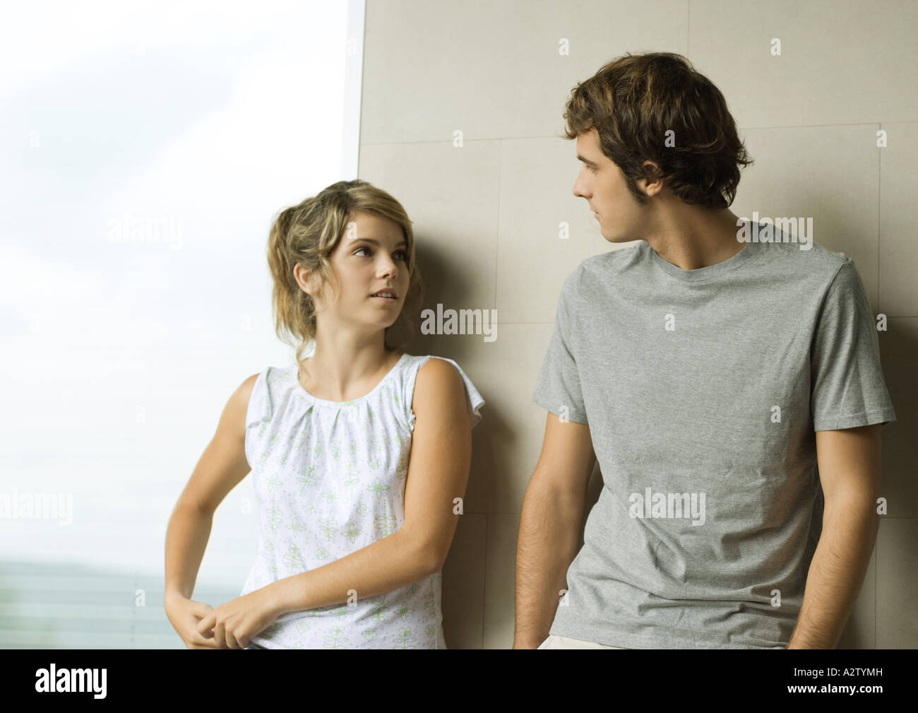 Young man and woman leaning against wall Stock Photo - Alamy