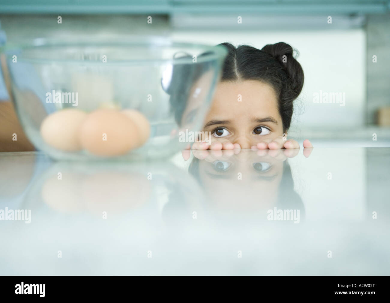 Girl looking over edge of counter at eggs in mixing bowl Stock Photo ...