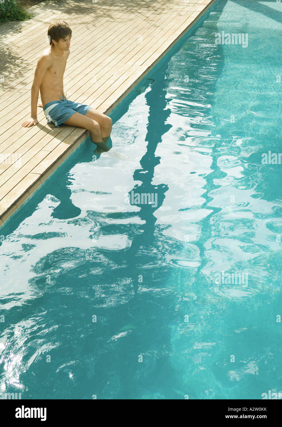 Teenage boy sitting on edge of swimming pool Stock Photo - Alamy