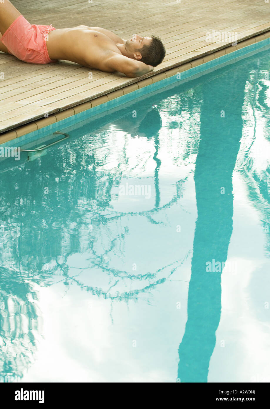 Man lying by edge of swimming pool Stock Photo - Alamy