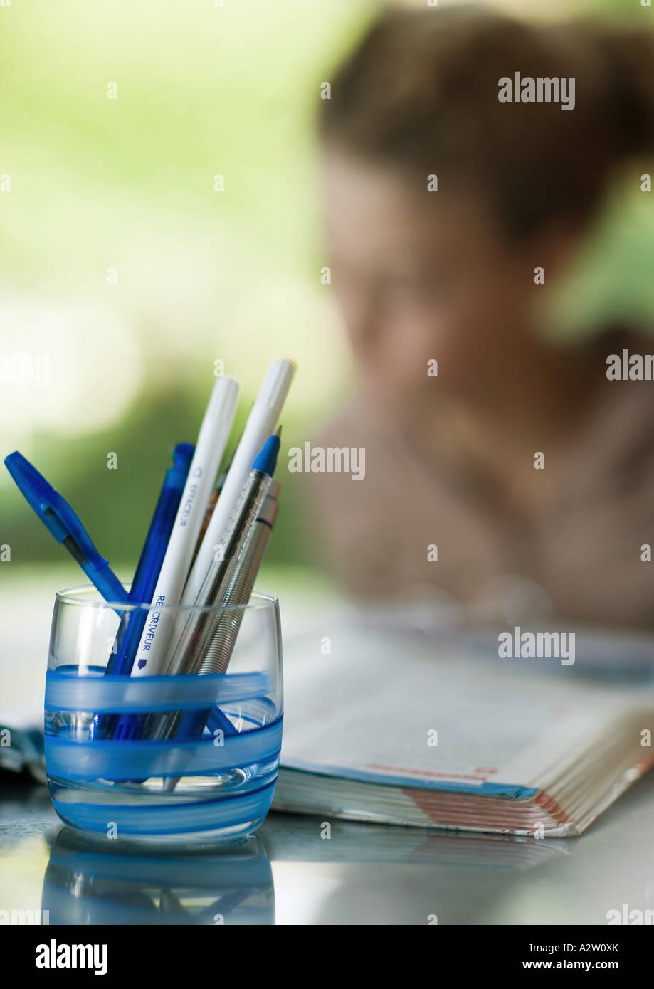 Glass full of pens, child doing homework in background Stock Photo - Alamy