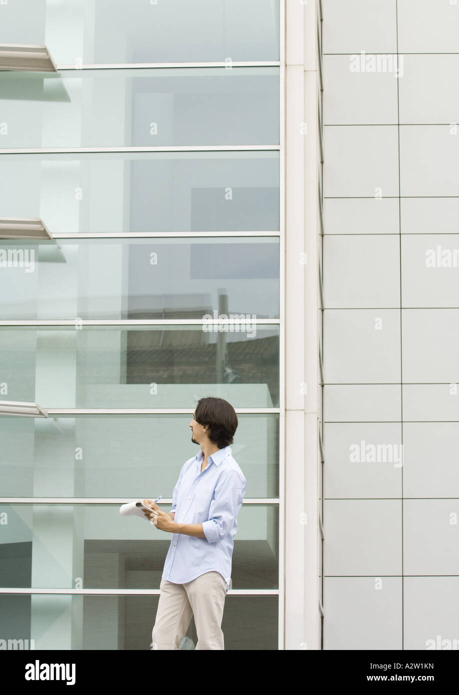 Man standing taking notes on pad of paper Stock Photo - Alamy