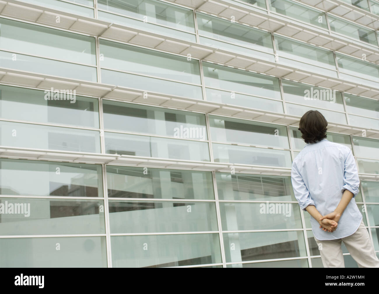 Man looking up at facade of office building Stock Photo - Alamy