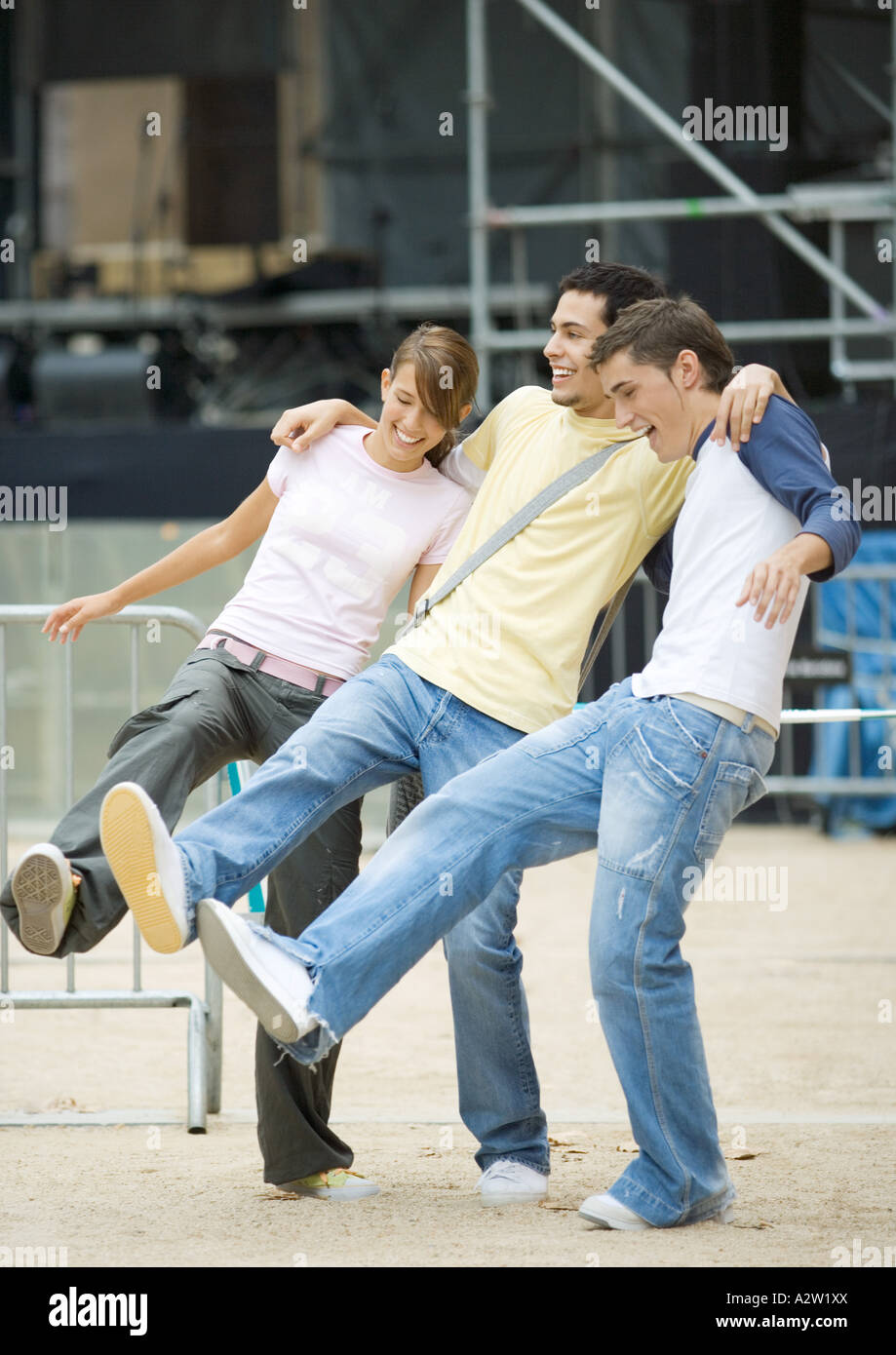 Three teenagers standing with arms around each others' shoulders and ...