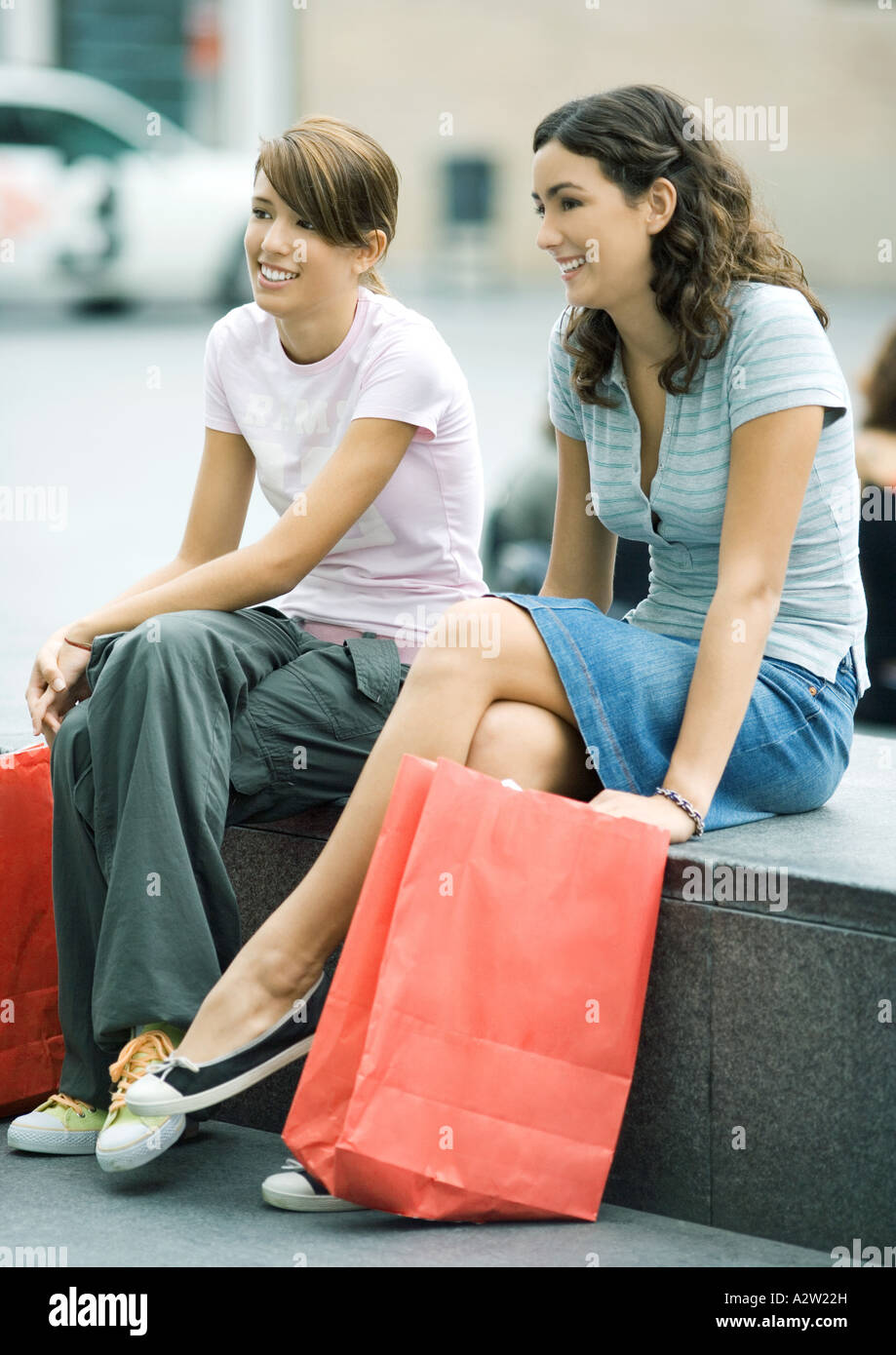 Two teenage girls sitting on bench with shopping bags Stock Photo - Alamy