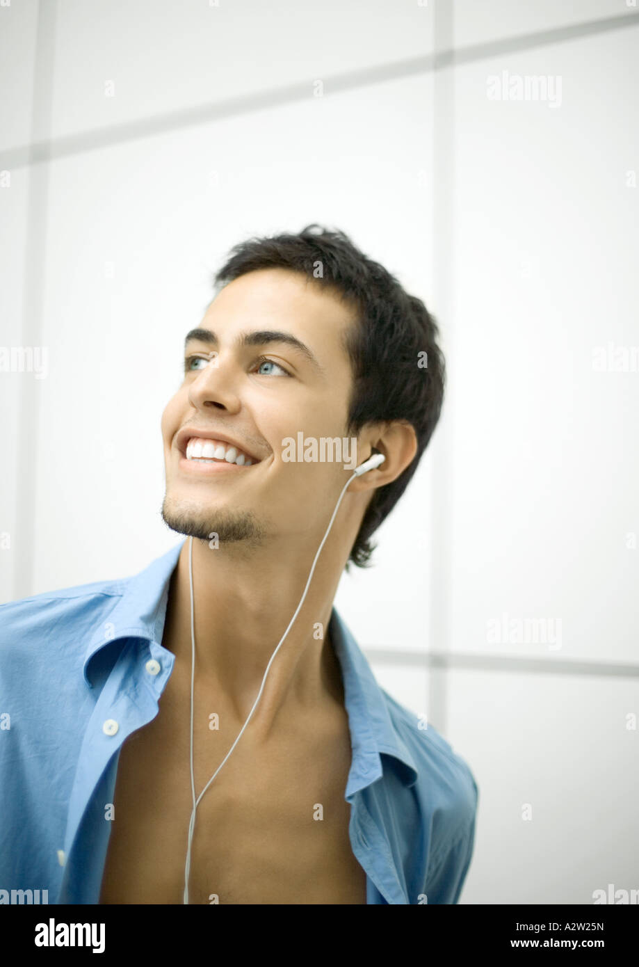 Young man listening to earphones, smiling Stock Photo - Alamy