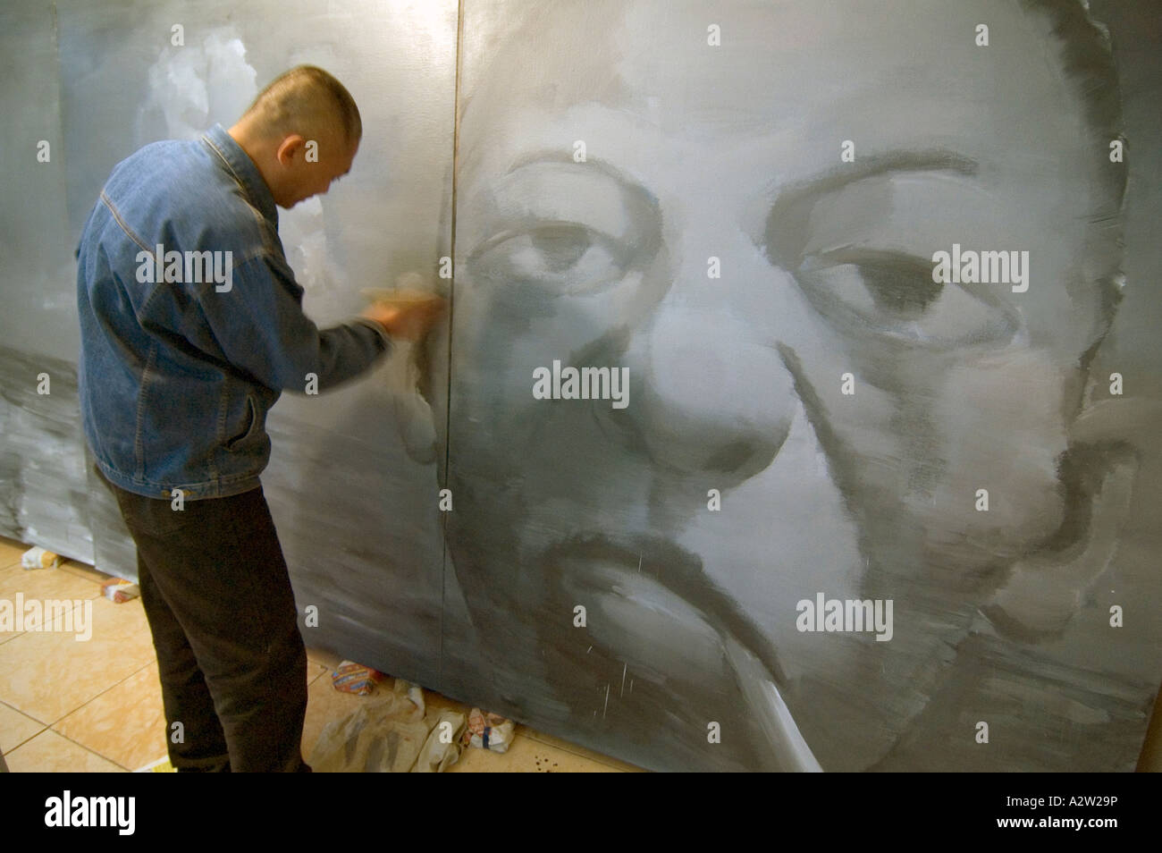 Portrait of a Chinese artist painting on a large canvas in the small ...