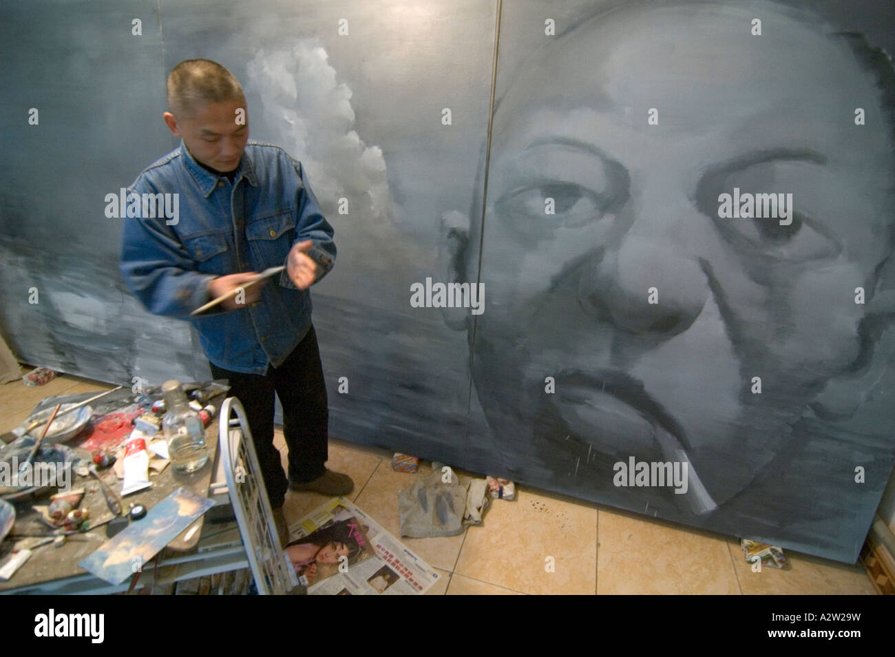 Portrait of a Chinese artist painting on a large canvas in the small ...
