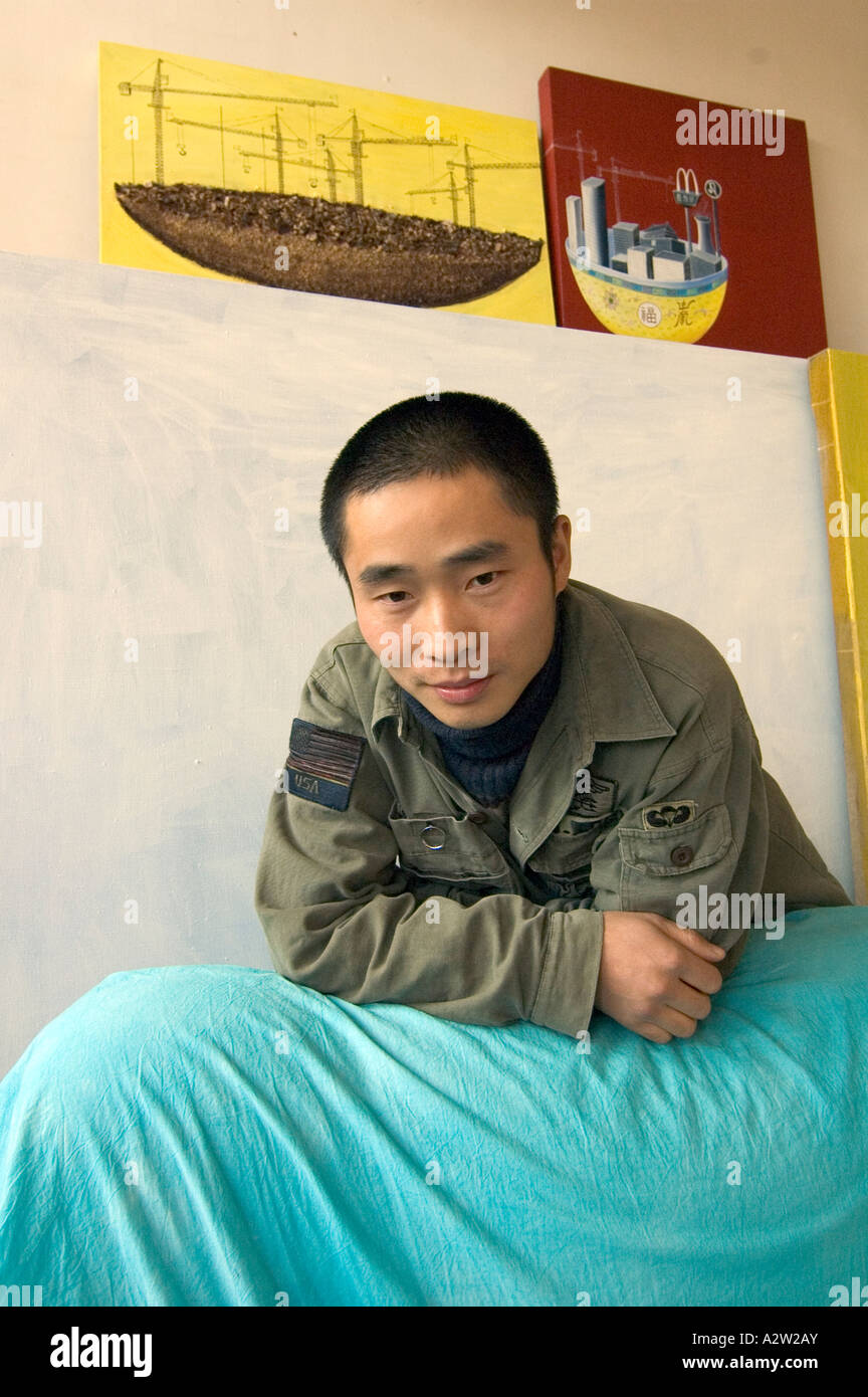 Portrait of a young Chinese artist in front of some of his paintings ...