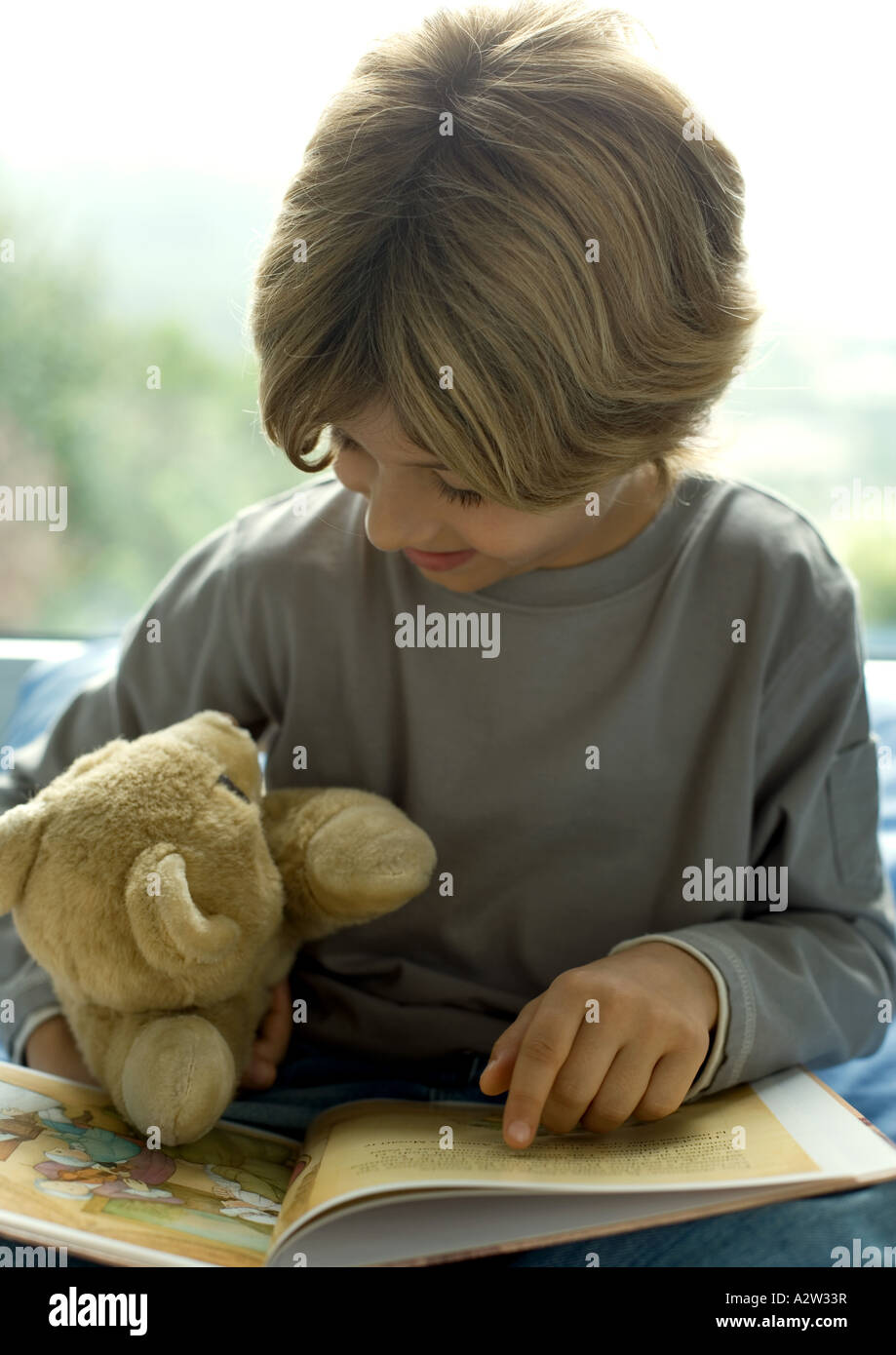 Child reading book to teddy bear Stock Photo - Alamy