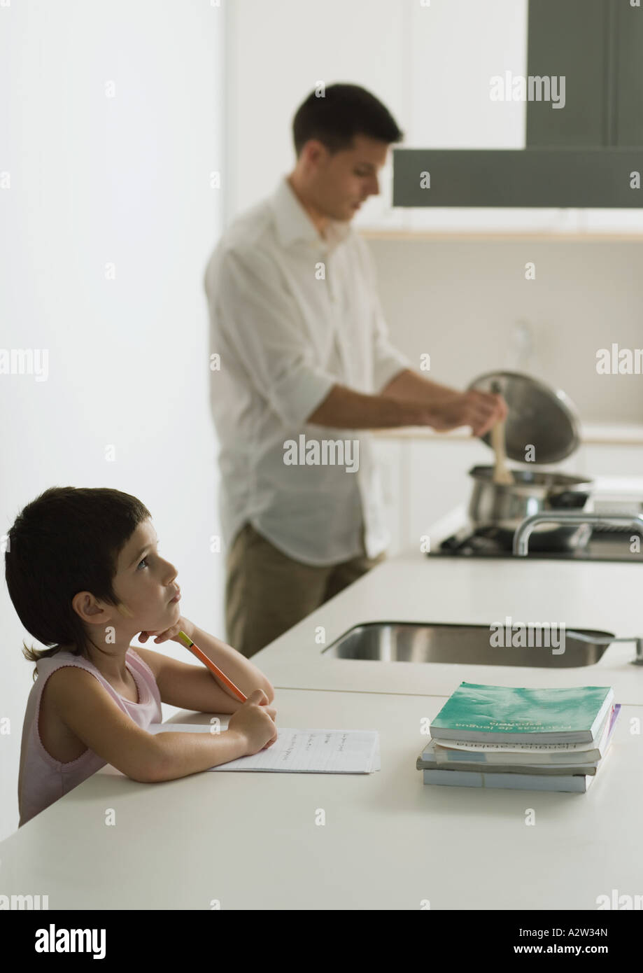 Child doing homework while father cooks meal Stock Photo - Alamy