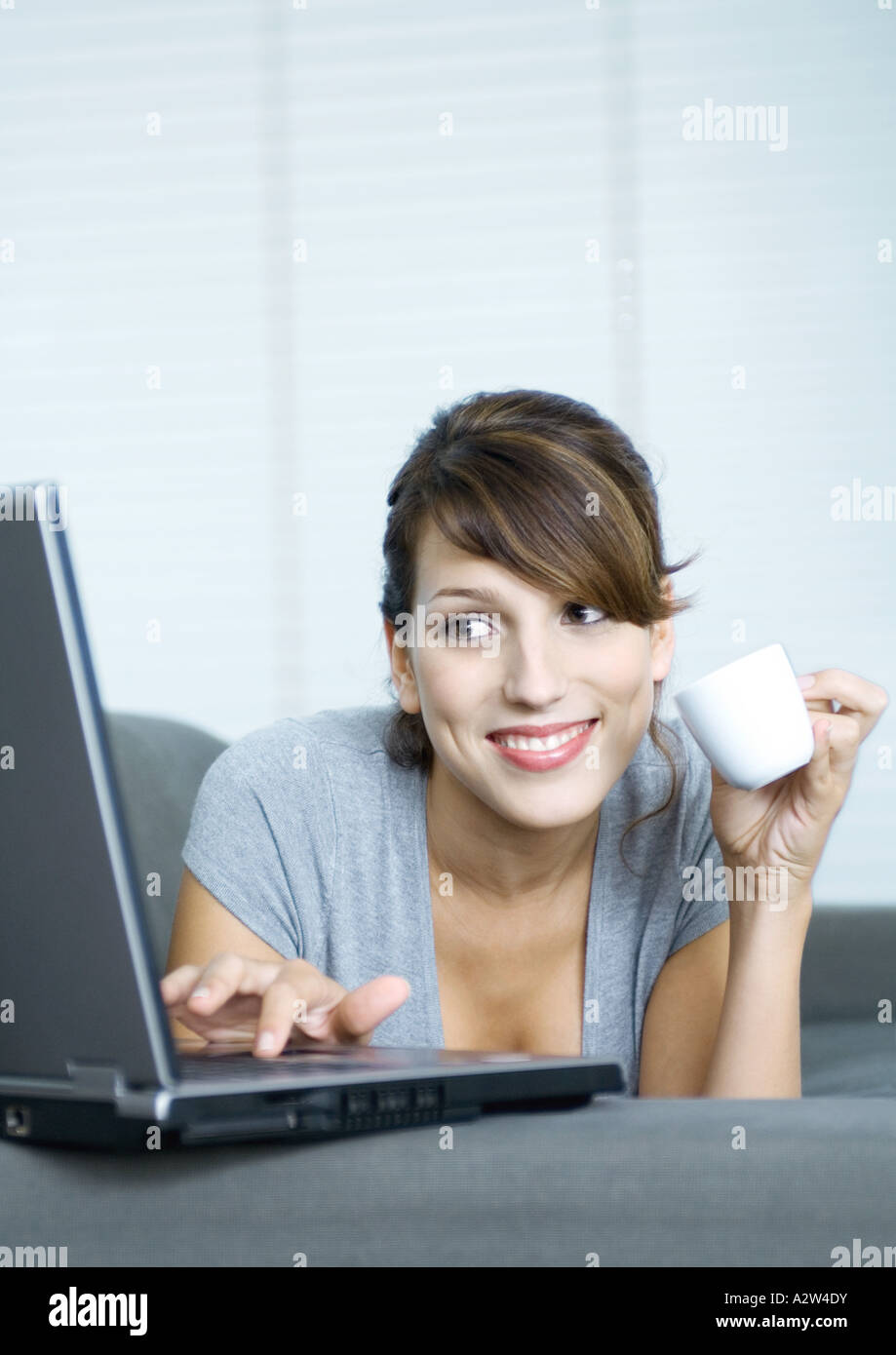 Woman drinking coffee and using laptop Stock Photo - Alamy