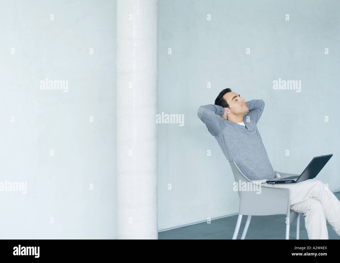 Man sitting with laptop on lap, head back and eyes closed Stock Photo ...