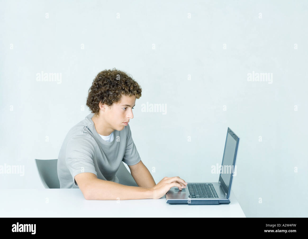 Young man using laptop computer at table Stock Photo - Alamy