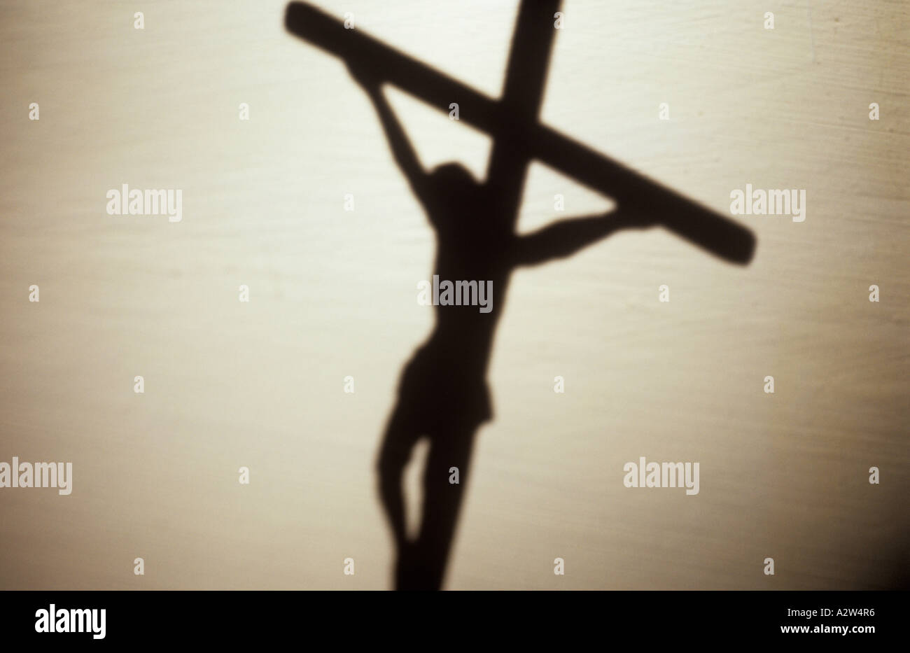A shadow or silhouette against a pale wall of Jesus Christ hanging from ...