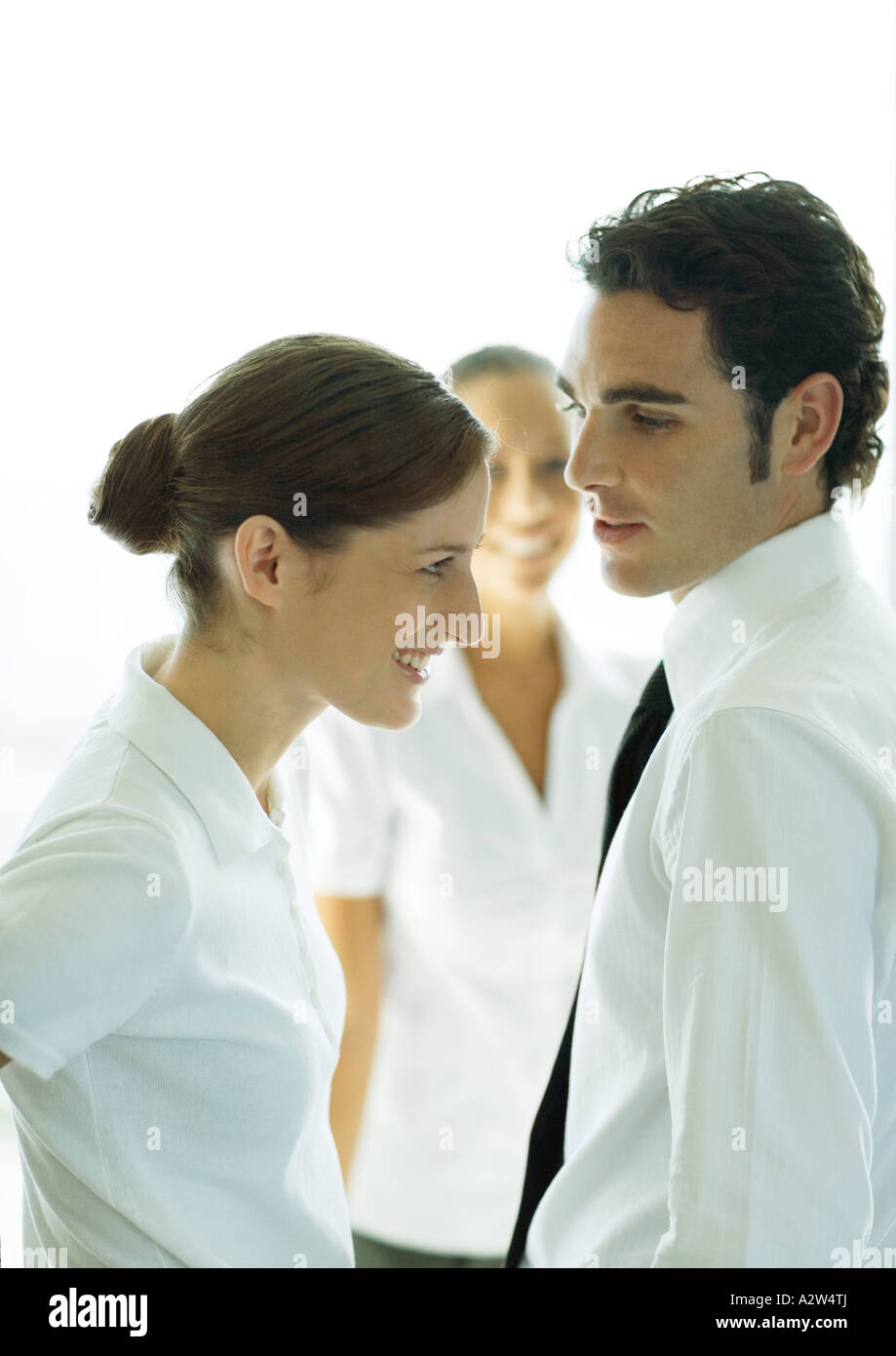 Young professional couple talking, second woman standing in background ...