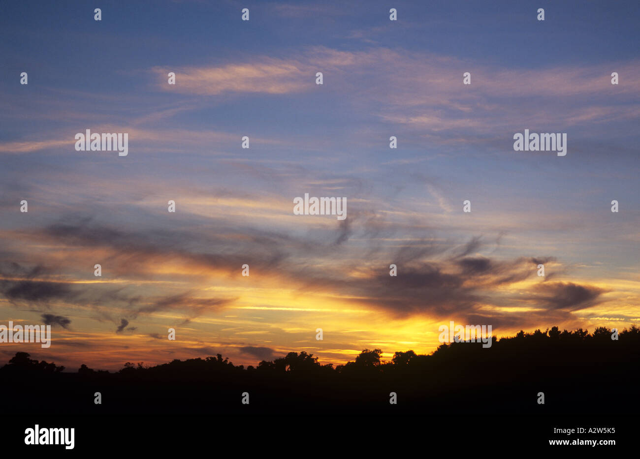 Scenic view of orange and blue sky with wispy cirrus clouds as sun sets ...