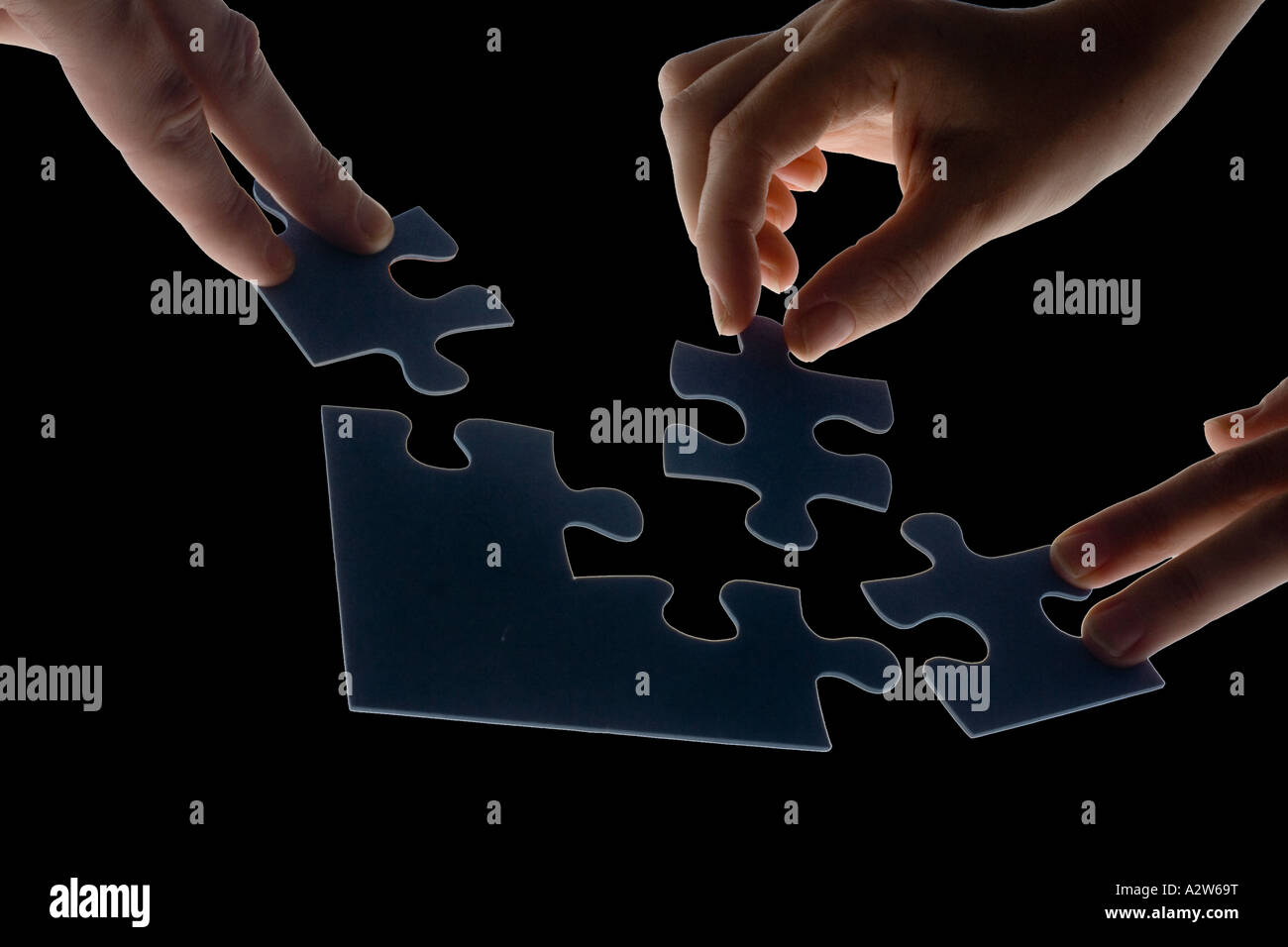 Hands working together to build a jigsaw Stock Photo - Alamy