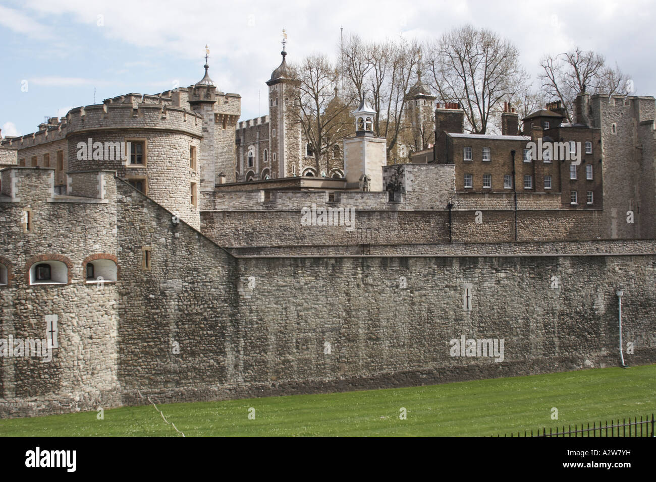 Tower of London walls with White Tower in distance and grass moat ditch ...