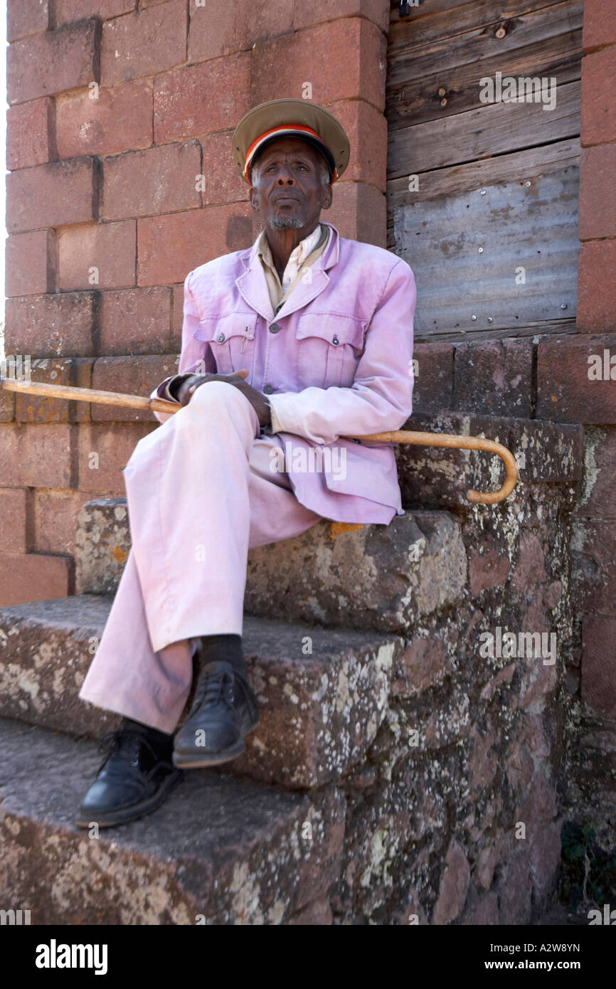 Security guard man in pink suit holding cane sitting on steps outside ...
