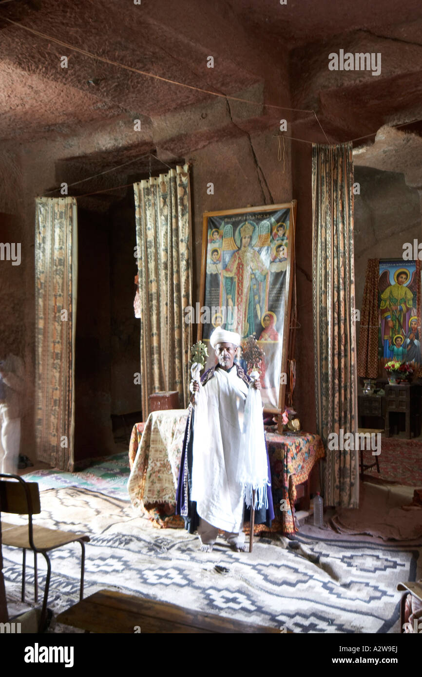 Priest with cross curtain drapes and paintings in Bet Gabriel Rafael ...