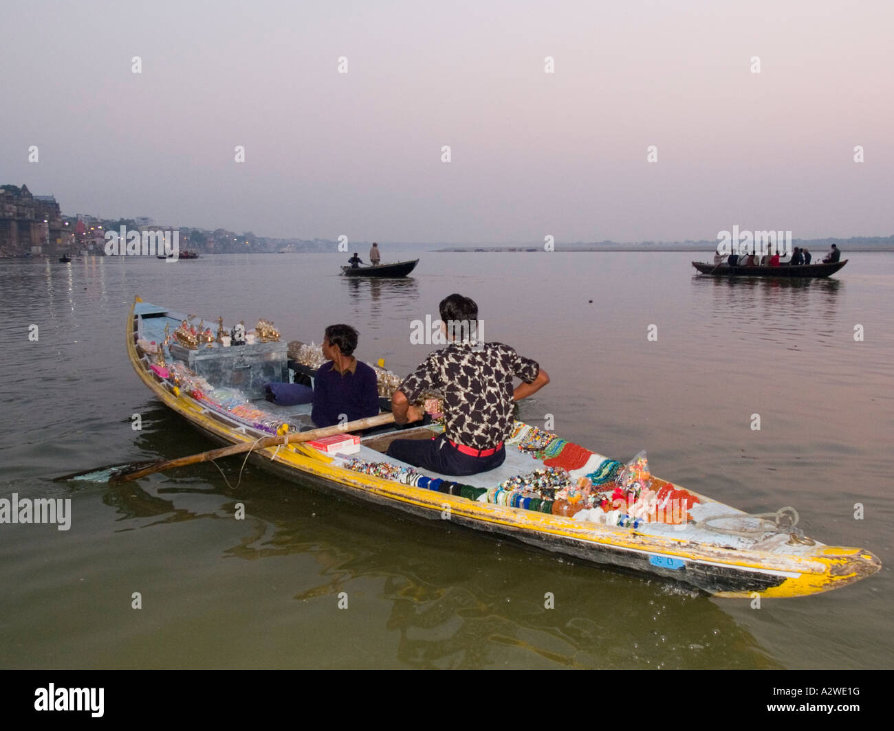 Indian men in rowing boat with souvenirs to sell following tourists on ...