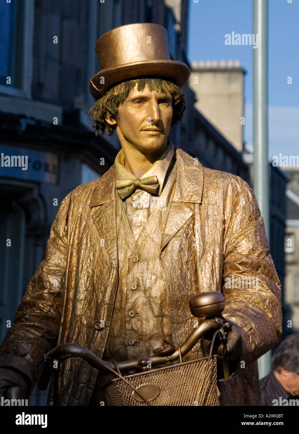 Mime artist dressed as a golden living statue with a bicycle entertains ...