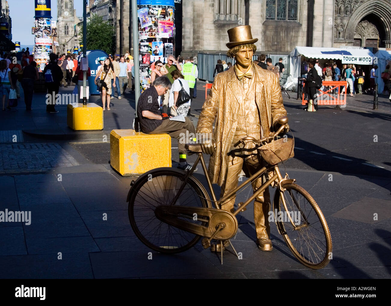 Mime artist dressed as a golden living statue with a bicycle entertains ...