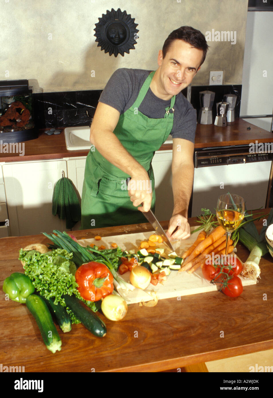 Young man cutting vegetables in kitchen, smiling, portrait Stock Photo ...