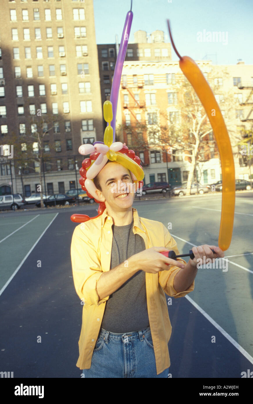 Young man inflating balloons, smiling Stock Photo - Alamy