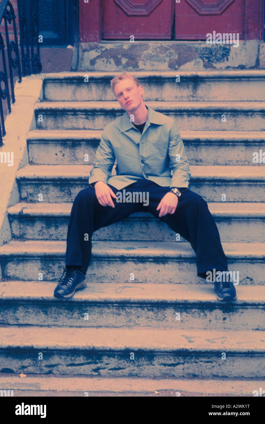 Young man sitting on staircase, portrait Stock Photo - Alamy